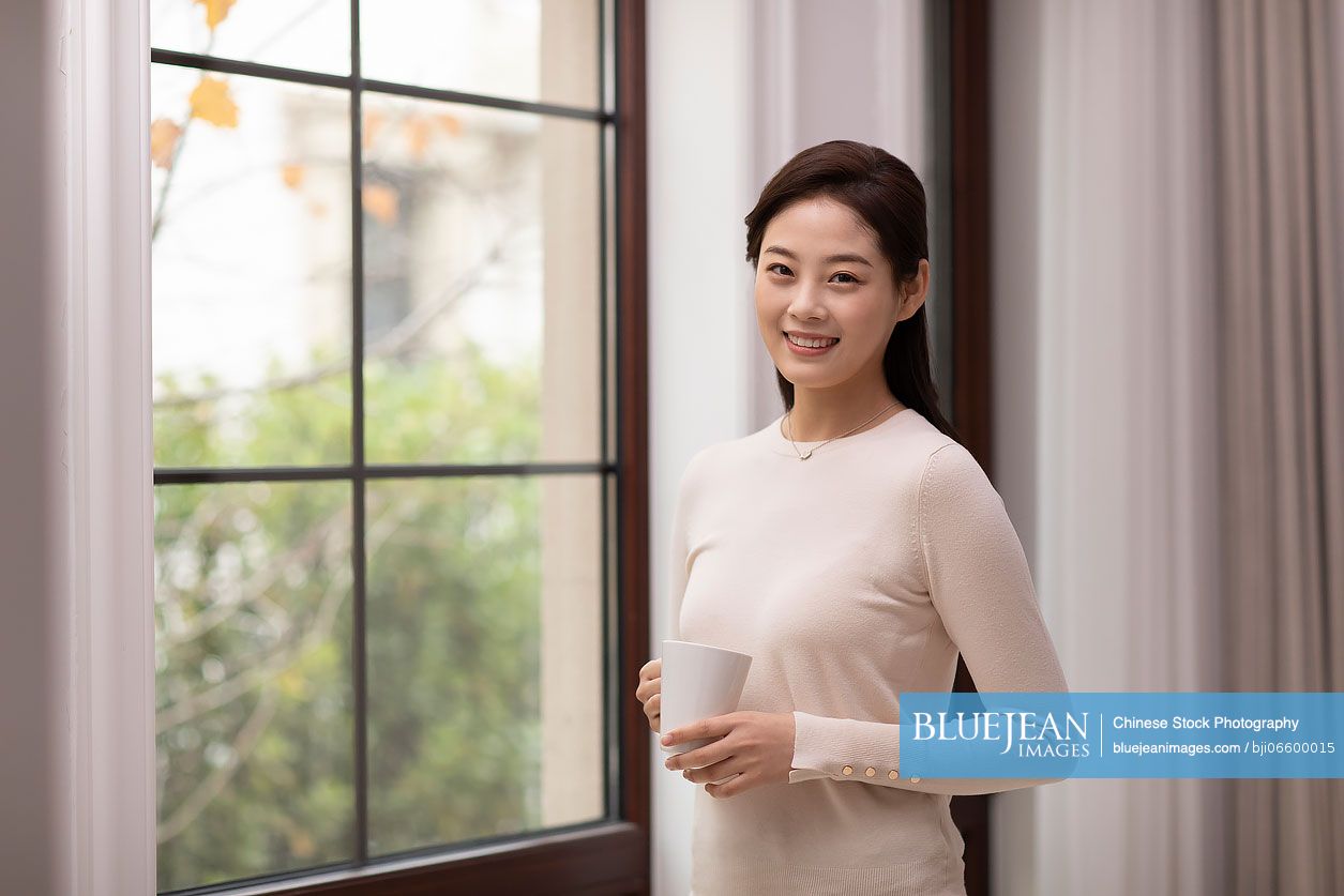 Happy young Chinese woman holding coffee-High-res stock photo for download