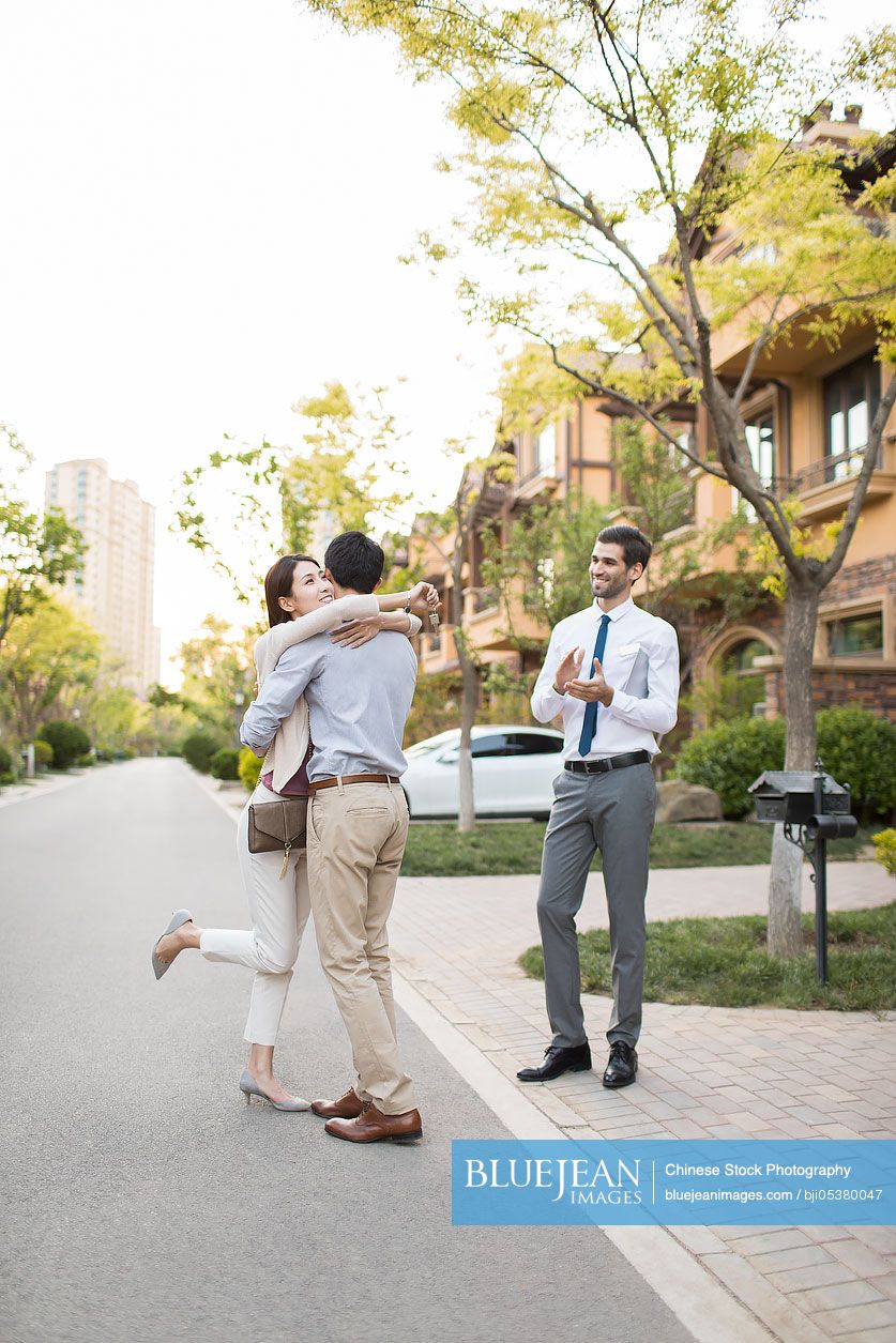 Happy young Chinese couple receiving house key from real estate agent ...