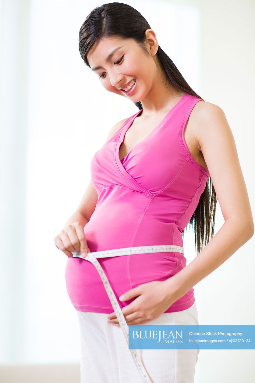 Young pregnant Chinese woman measuring waistline-High-res stock photo ...