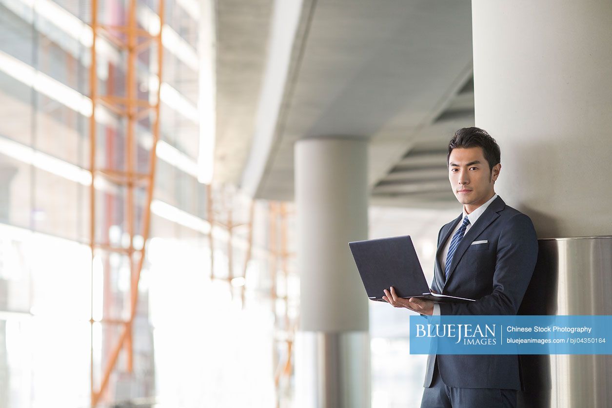 Young Chinese businessman using laptop in airport-High-res stock photo for download