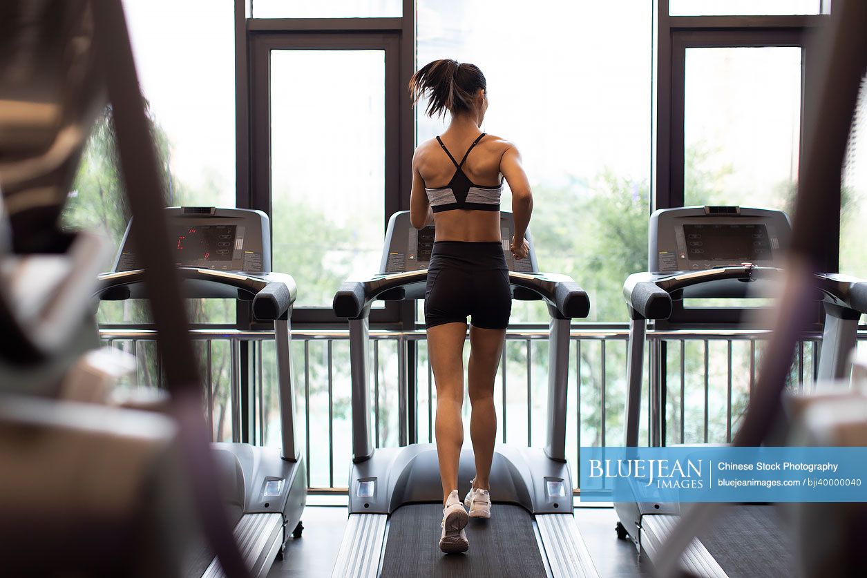 Young Chinese woman running on treadmill at gym-High-res stock photo ...