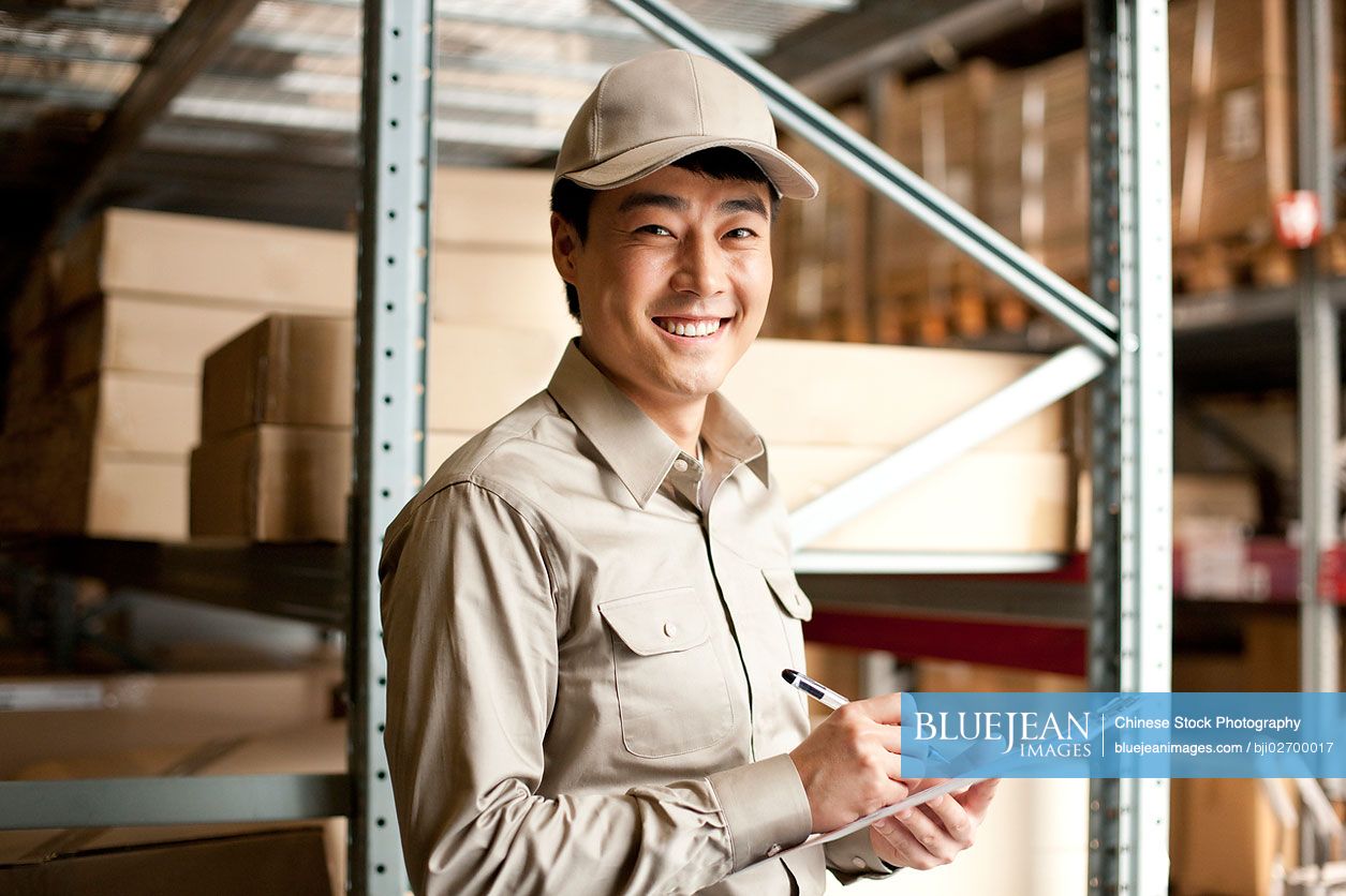 Male Chinese warehouse worker with clipboard-High-res stock photo for ...