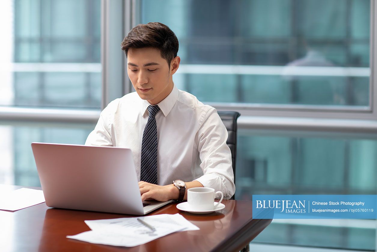 Confident Chinese businessman using laptop in office-High-res stock photo for download
