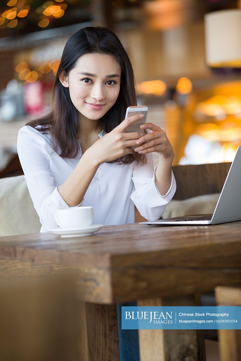 Young Chinese woman using smart phone in cafe-High-res stock photo for ...