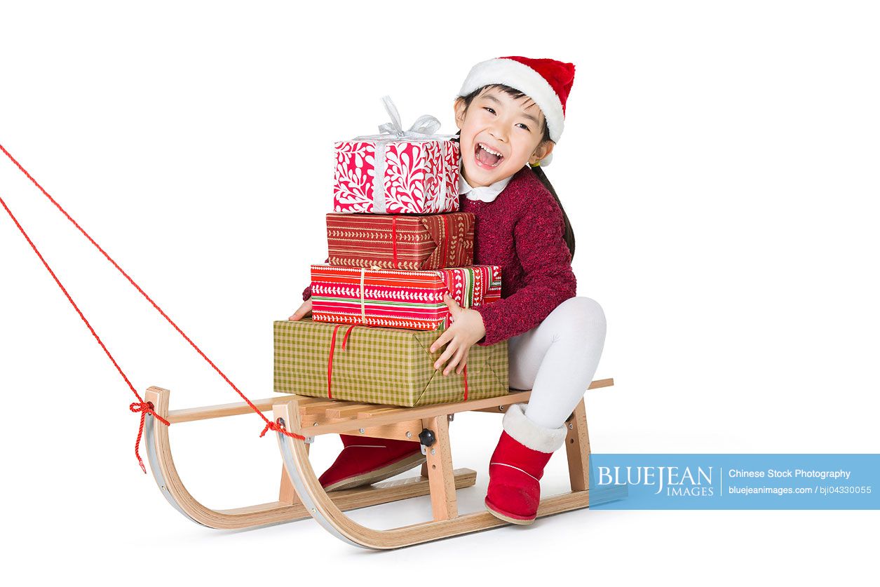 Happy Chinese girl with Christmas gifts on sled-High-res stock photo for download