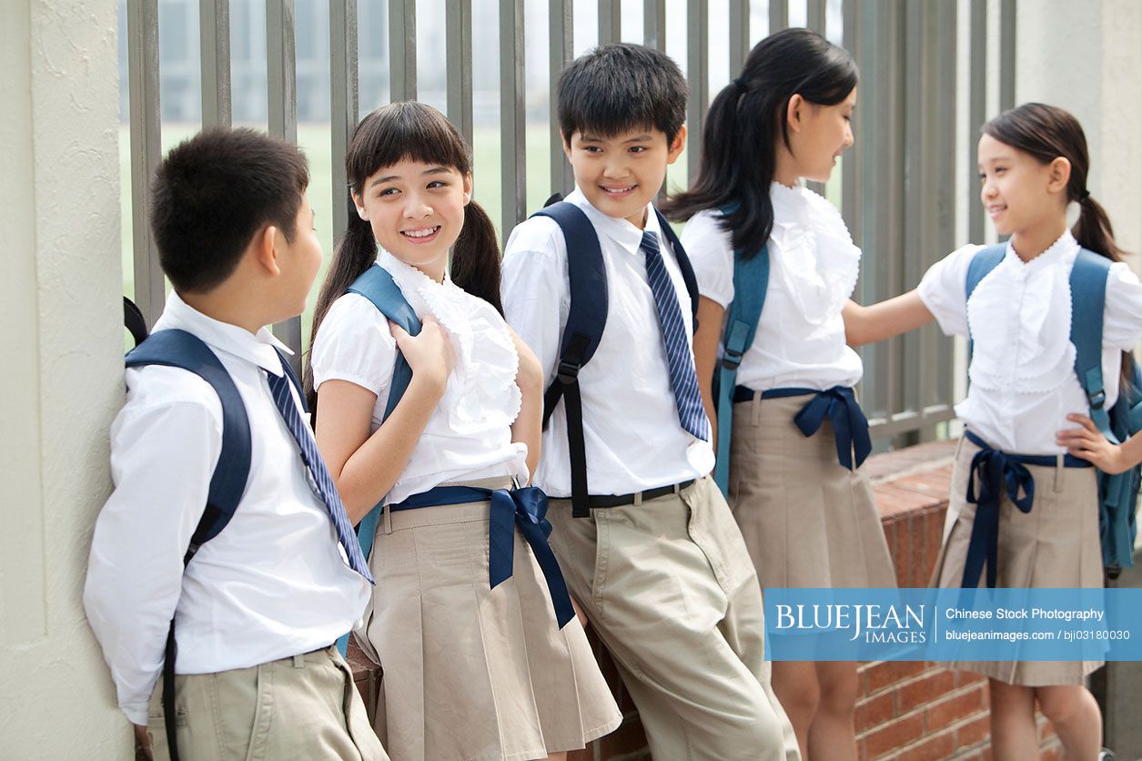 Cute Chinese schoolchildren in uniform leaning against a fence-High-res ...