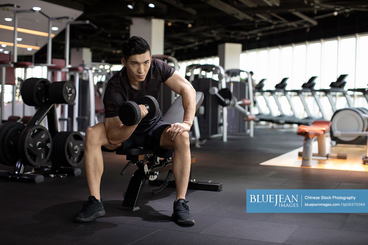 Young Chinese man working out with dumbbell at gym-High-res stock photo ...
