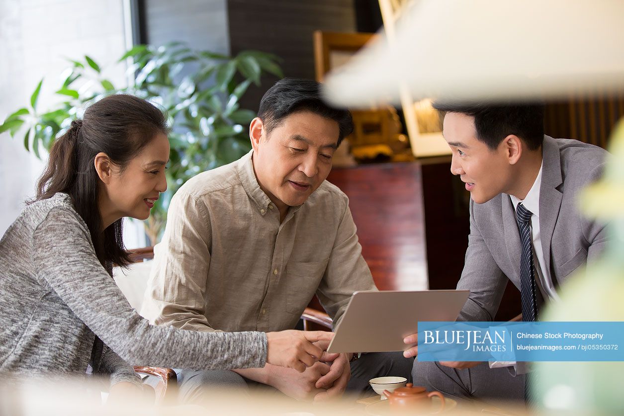 Confident Chinese financial consultant talking with mature couple-High ...