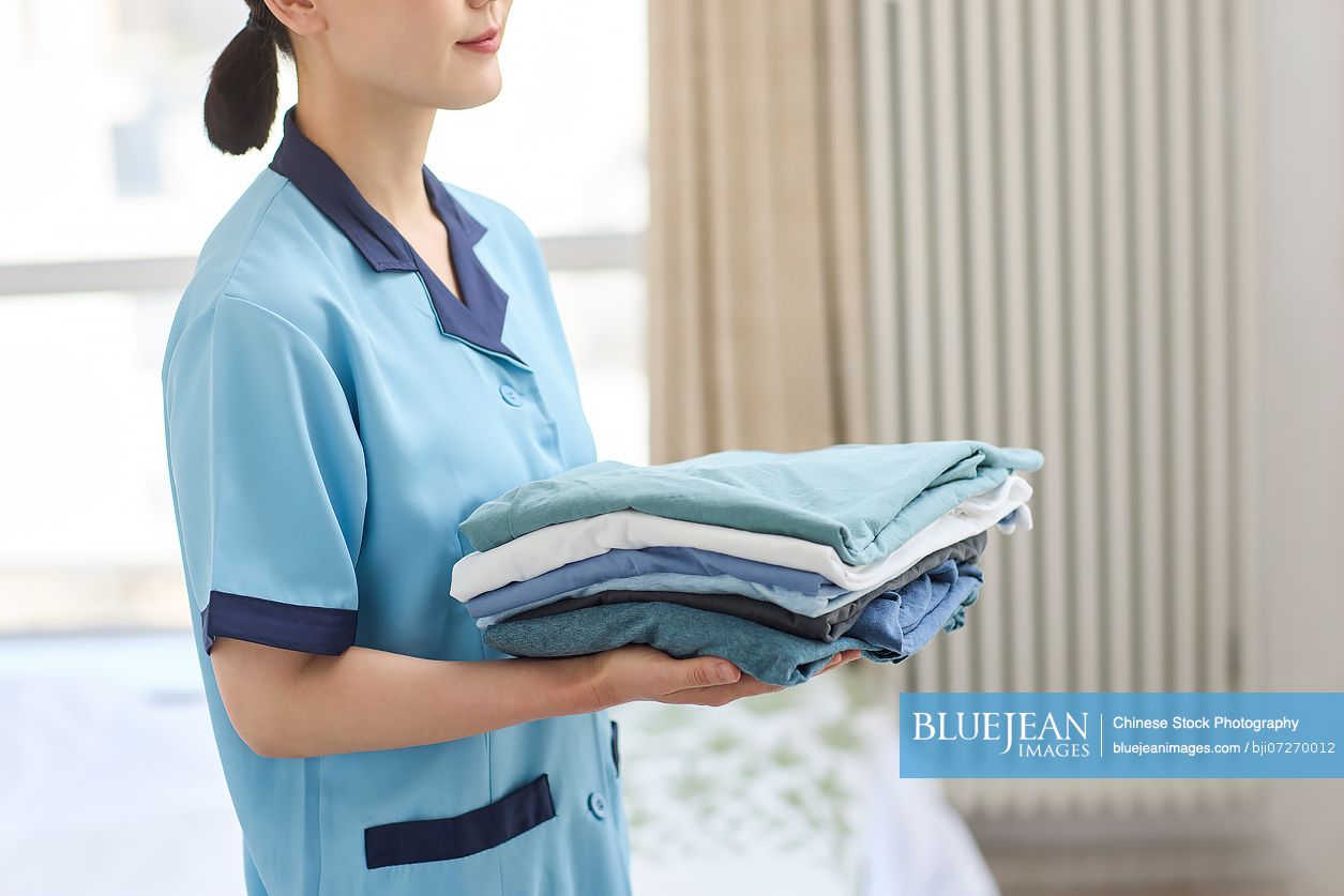 Female cleaner folding freshly laundered clothes-High-res stock photo ...