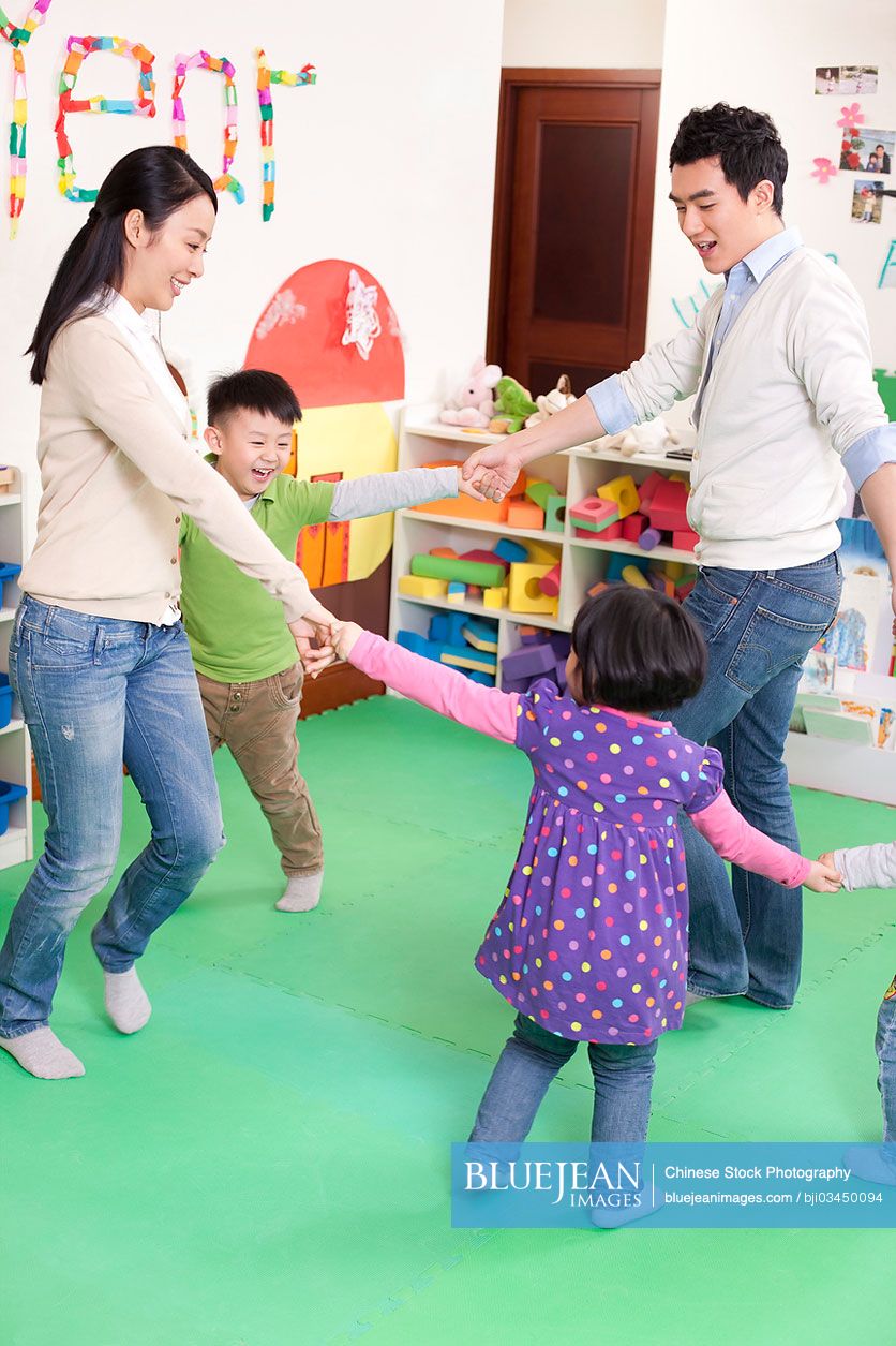 Cheerful Chinese kindergarten children playing games with teachers-High ...