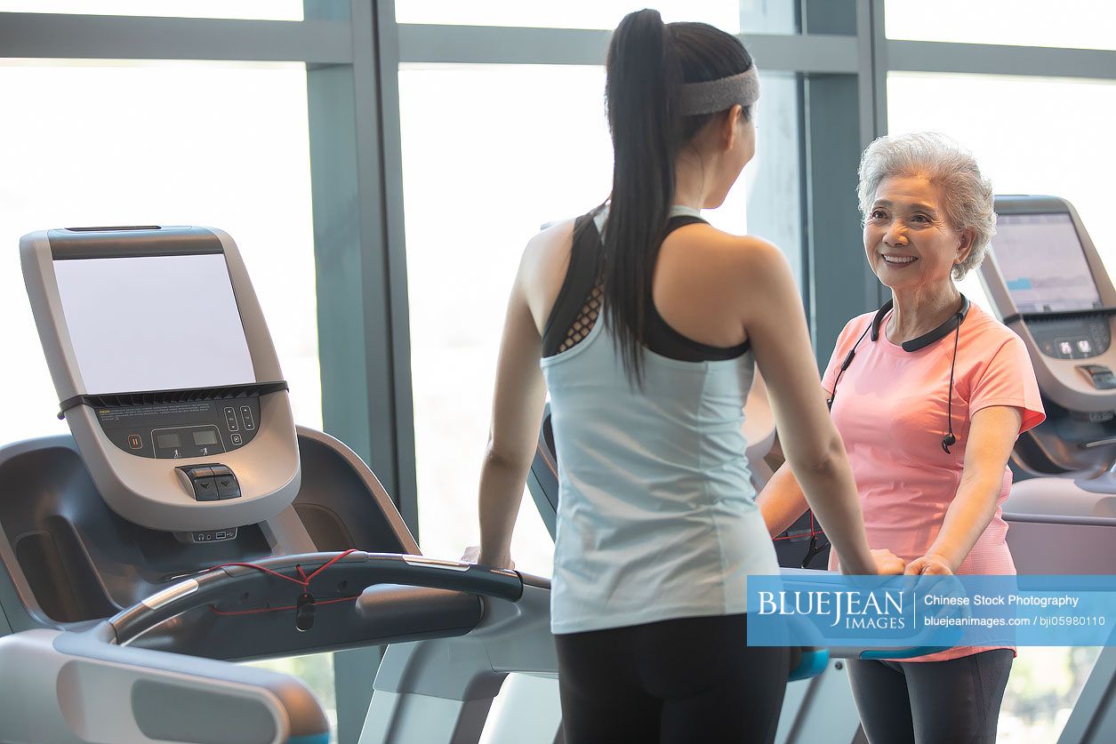 Senior Chinese woman working out with personal trainer at gym-High-res ...
