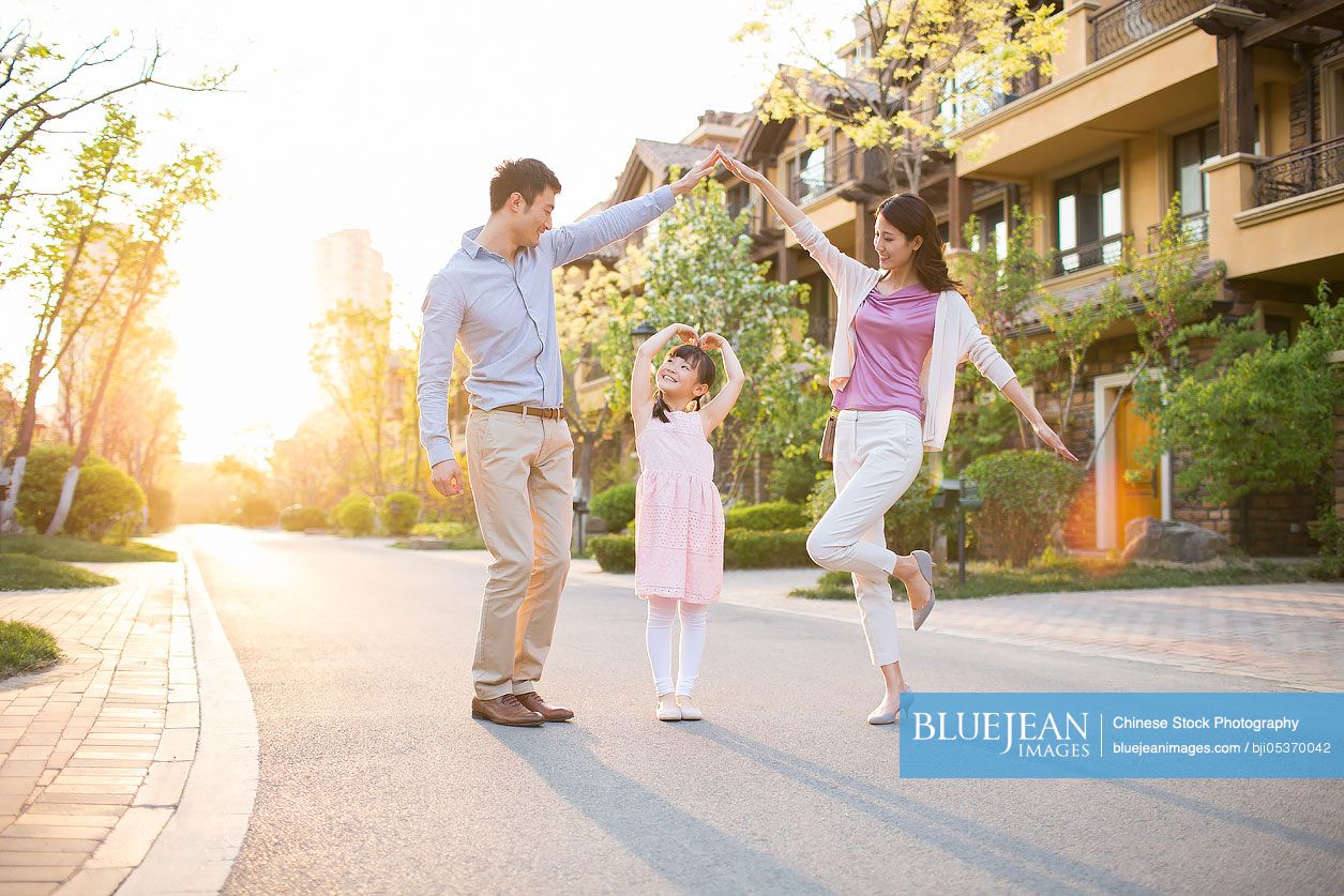 Happy young Chinese family standing in front of their new house-High ...
