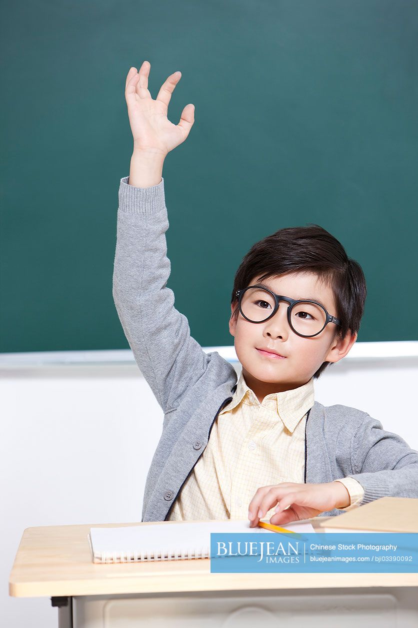 Lovely Chinese schoolboy raising hand in classroom-High-res stock photo ...