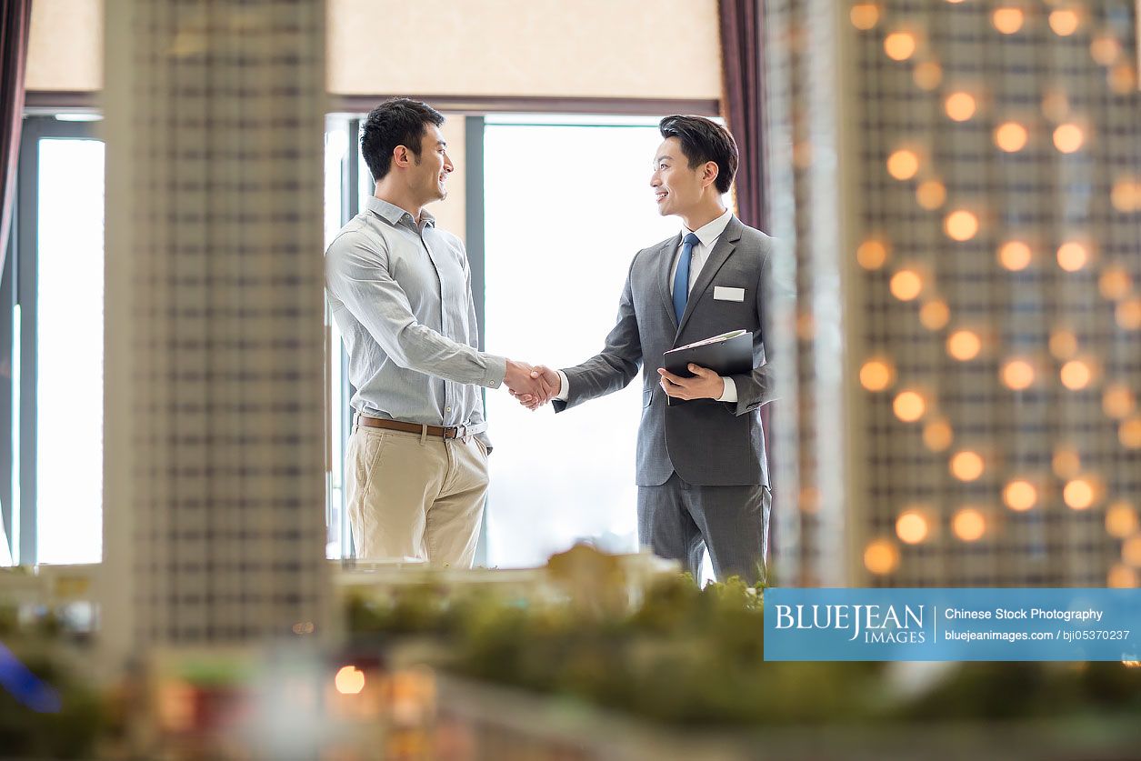 Happy young Chinese man shaking hands with realtor-High-res stock photo ...