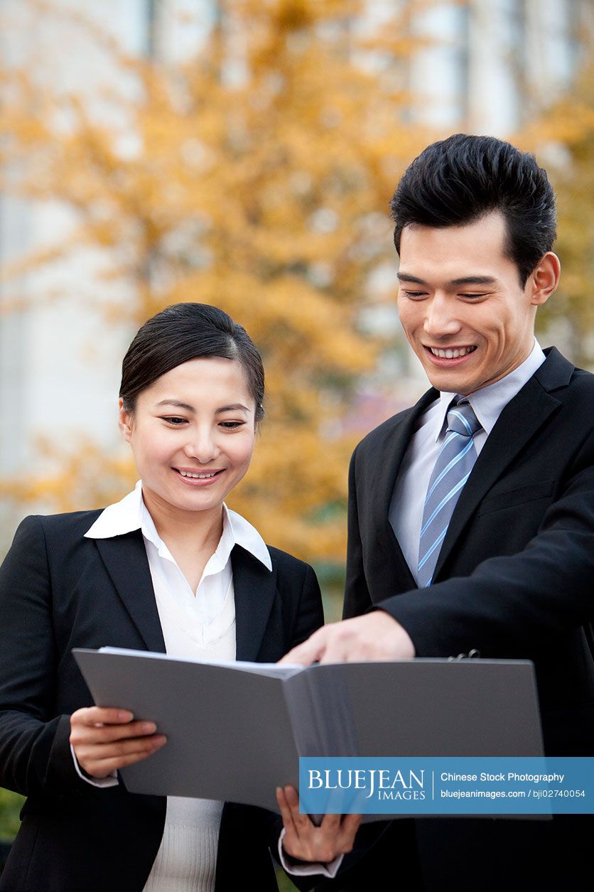 A Chinese businessman and businesswoman outside office buildings ...