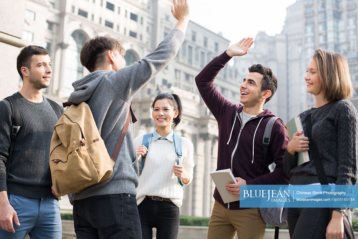 Cheerful abroad students high fiving on campus-High-res stock photo for ...
