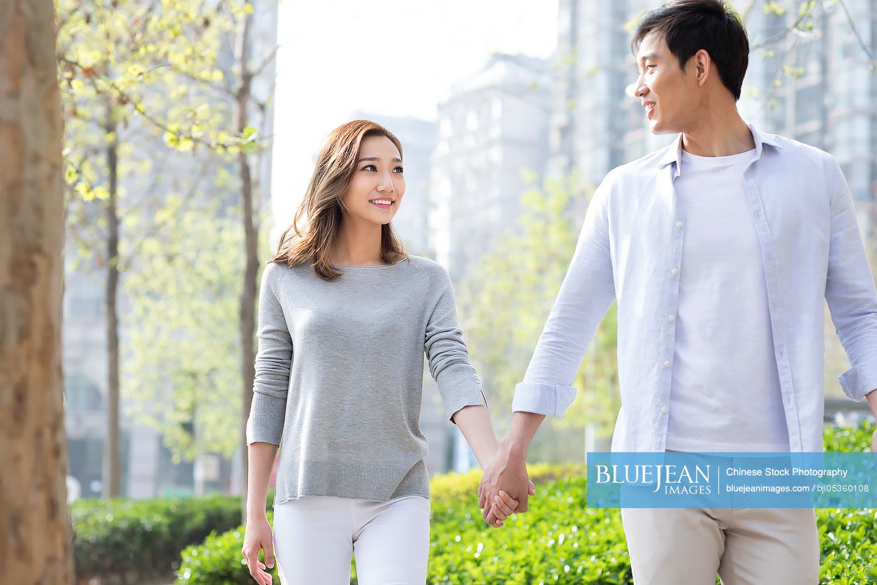 Happy young Chinese couple holding hands walking-High-res stock photo for download