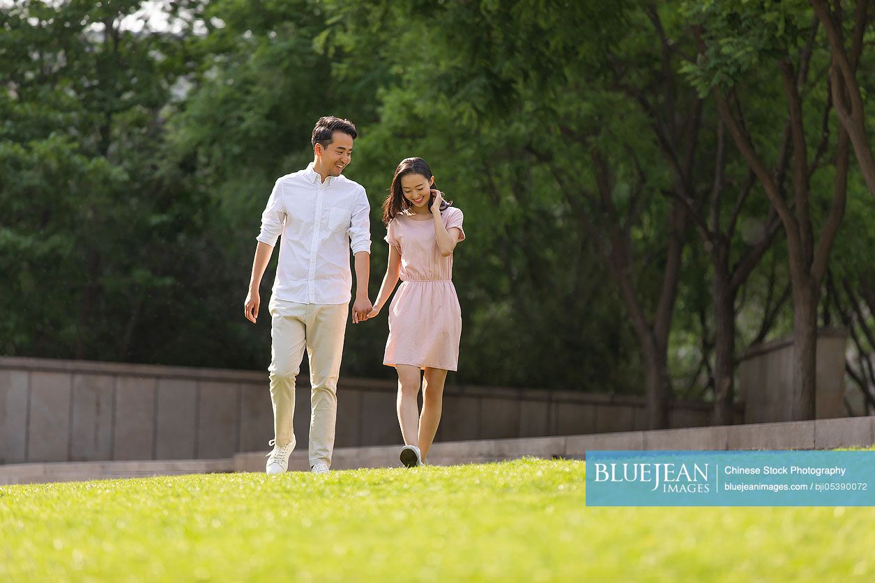 Happy young Chinese couple walking in park-High-res stock photo for download