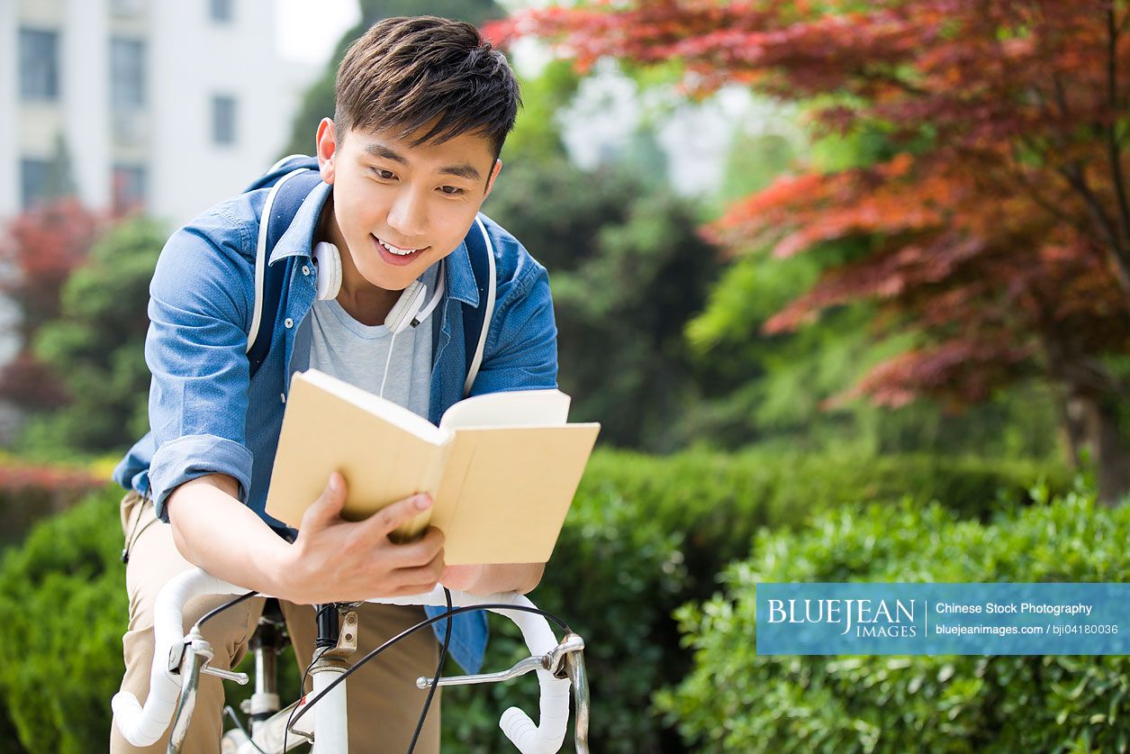 Male Chinese college student Reading on bicycle-High-res stock photo ...