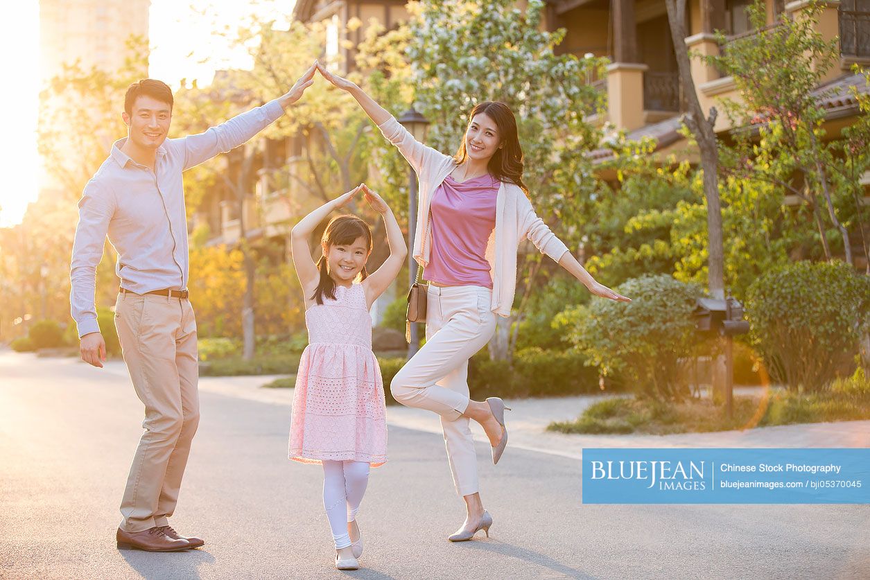 Happy young Chinese family standing in front of their new house-High ...