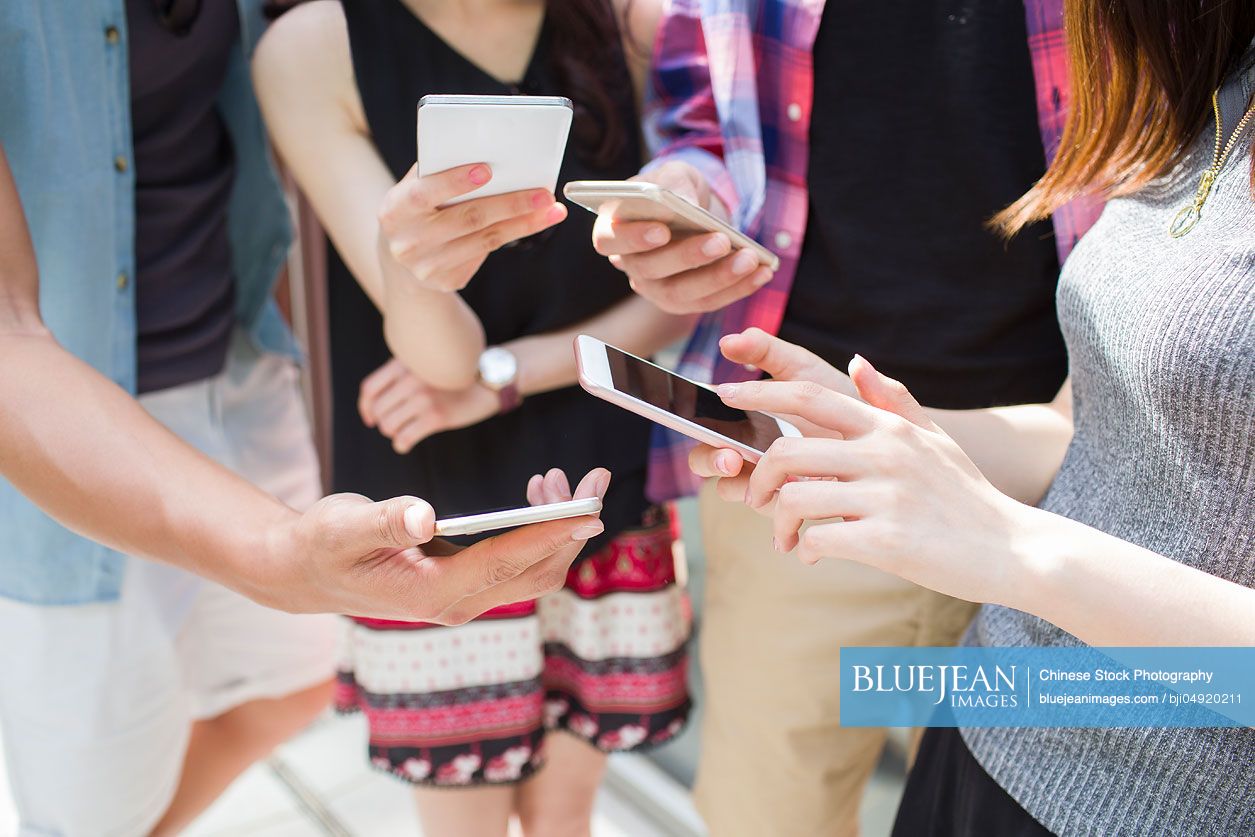 Young Chinese friends looking at smart phones-High-res stock photo for ...