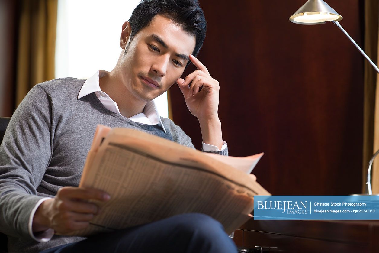 Young Chinese Businessman Reading Newspaper In Study High res Stock Young Chinese Businessman Reading Newspaper In Study High res Stock