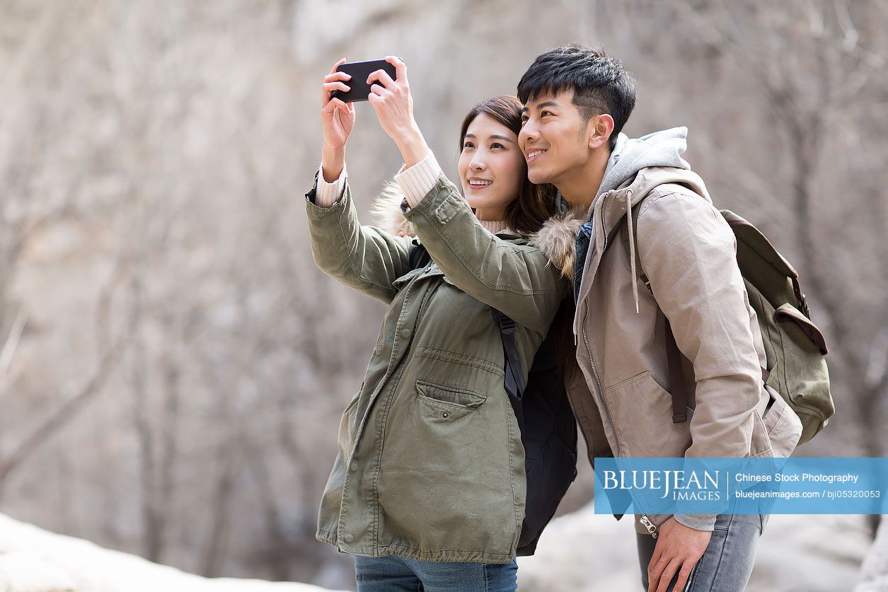 Happy young Chinese couple taking selfies outdoors in winter-High-res stock photo for download