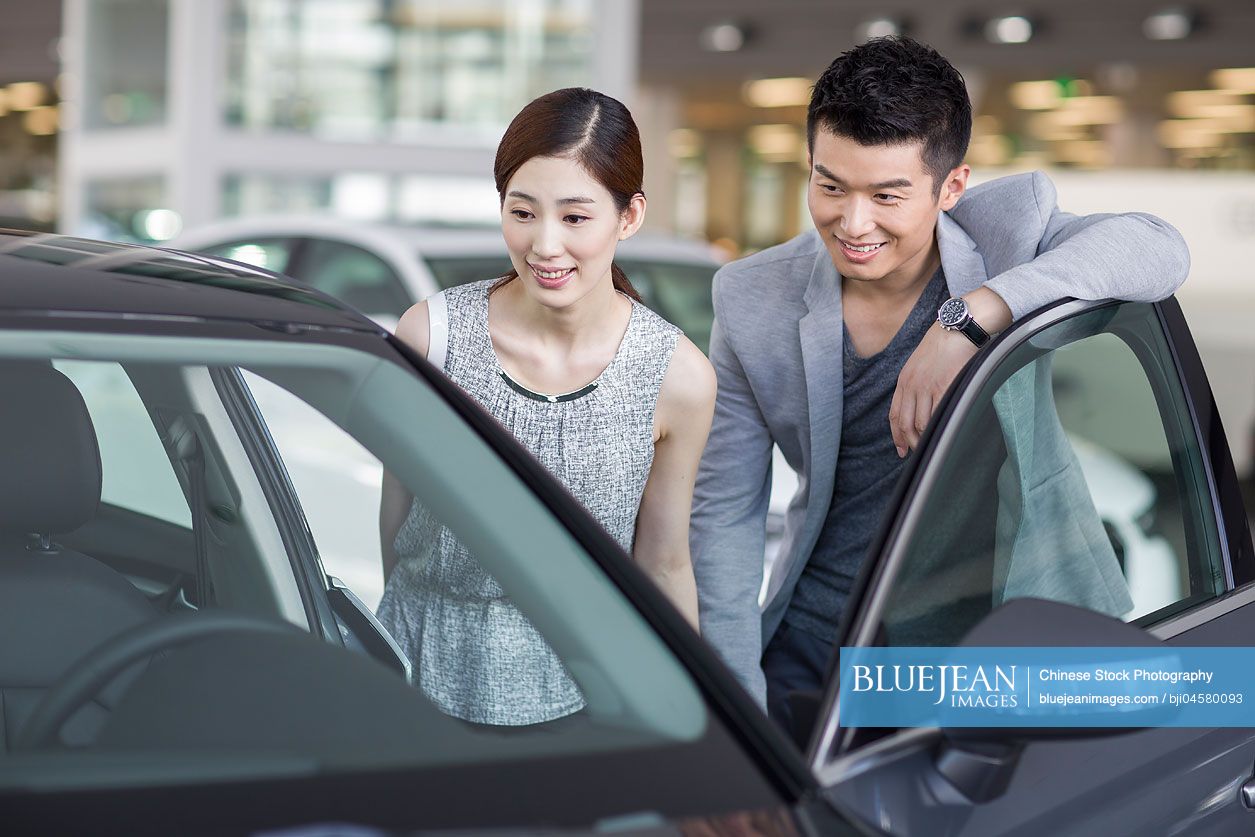 Young Chinese couple looking at new car in showroom-High-res stock ...