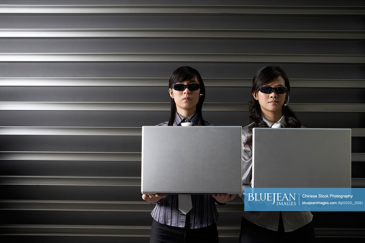 Serious Chinese businesswoman holding laptops-High-res stock photo for download