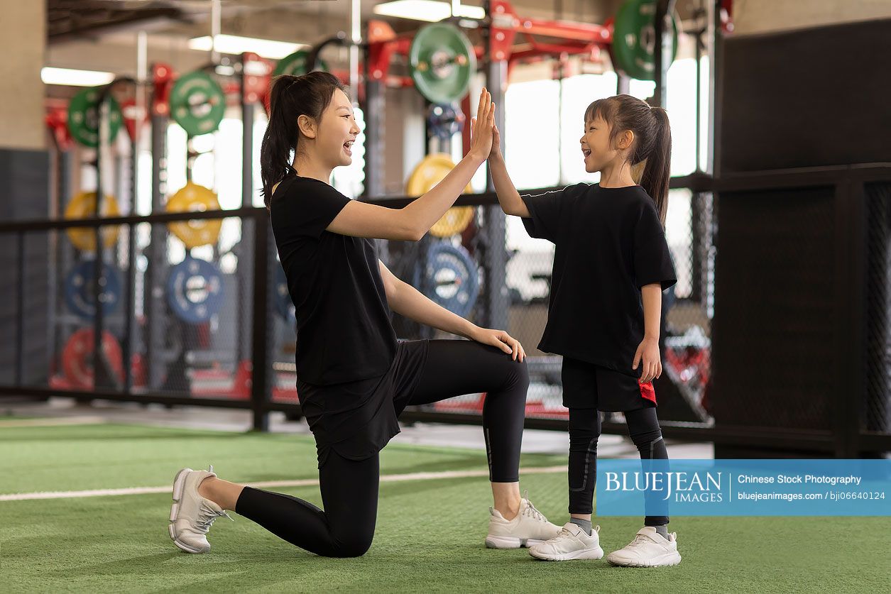 Cute Chinese girl and coach high fiving in gym-High-res stock photo for ...