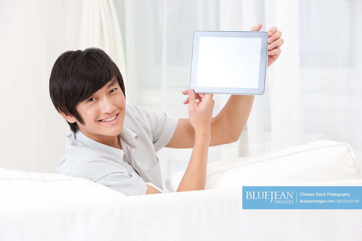 Young Chinese man using tablet at home-High-res stock photo for download