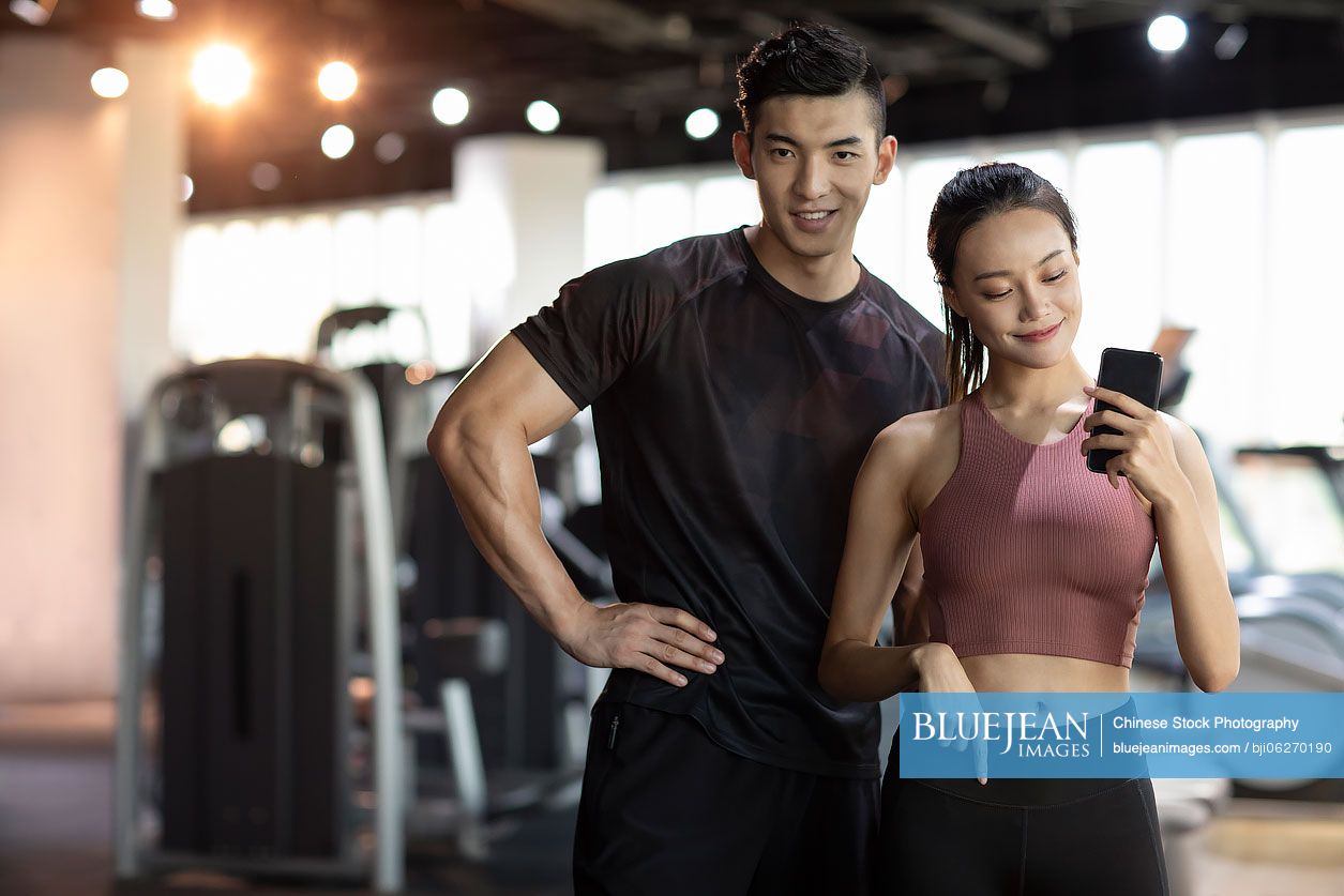 Young Chinese couple taking selfie with smartphone at gym-High-res ...