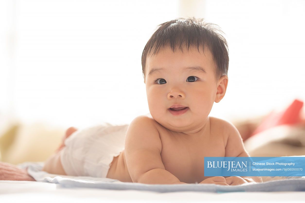 Little Chinese baby lying on front in bed-High-res stock photo for download