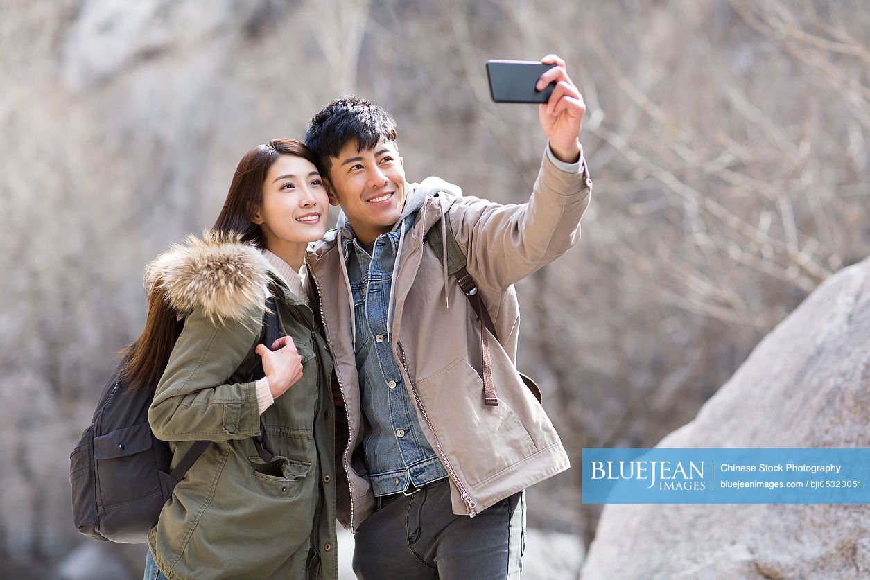 Happy young Chinese couple taking selfies outdoors in winter-High-res stock photo for download
