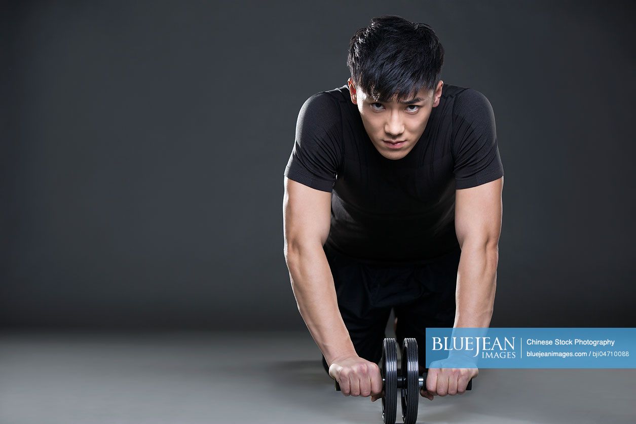 Young Chinese man exercising with Ab wheel-High-res stock photo for ...