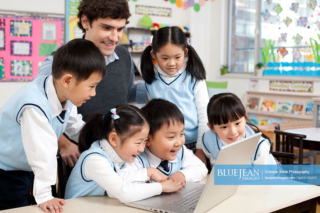 Chinese students and teacher gathered around a computer in the ...