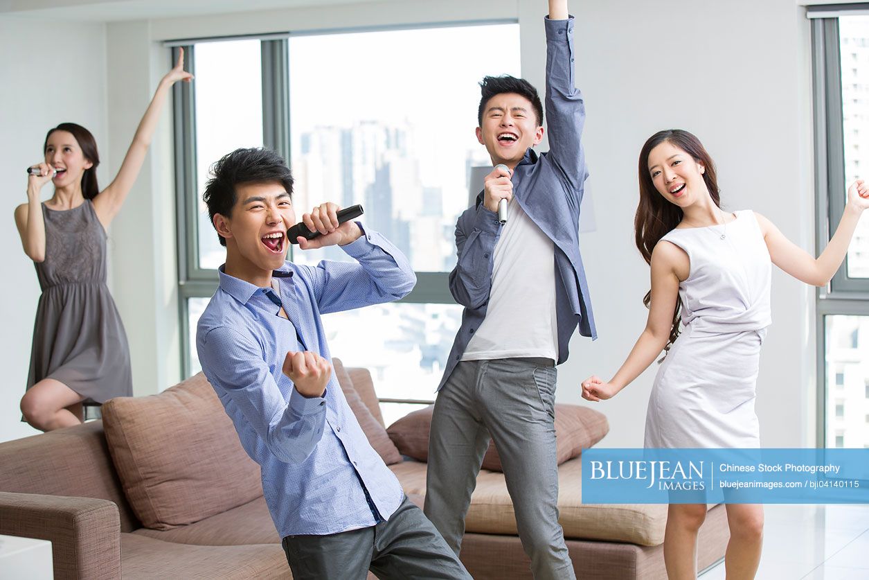 Happy young Chinese friends singing and dancing in living room-High-res ...