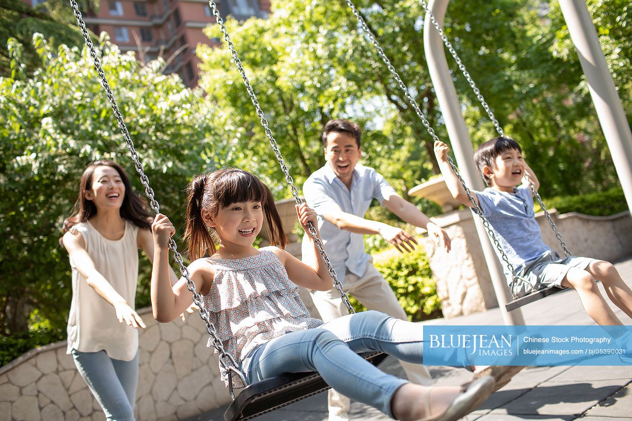 Happy young Chinese family playing on swings-High-res stock photo for ...