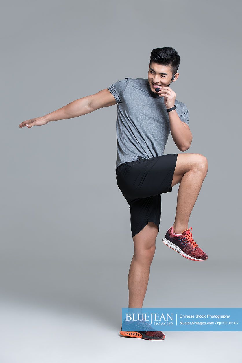 Cheerful young Chinese male trainer with headset teaching at gym-High ...