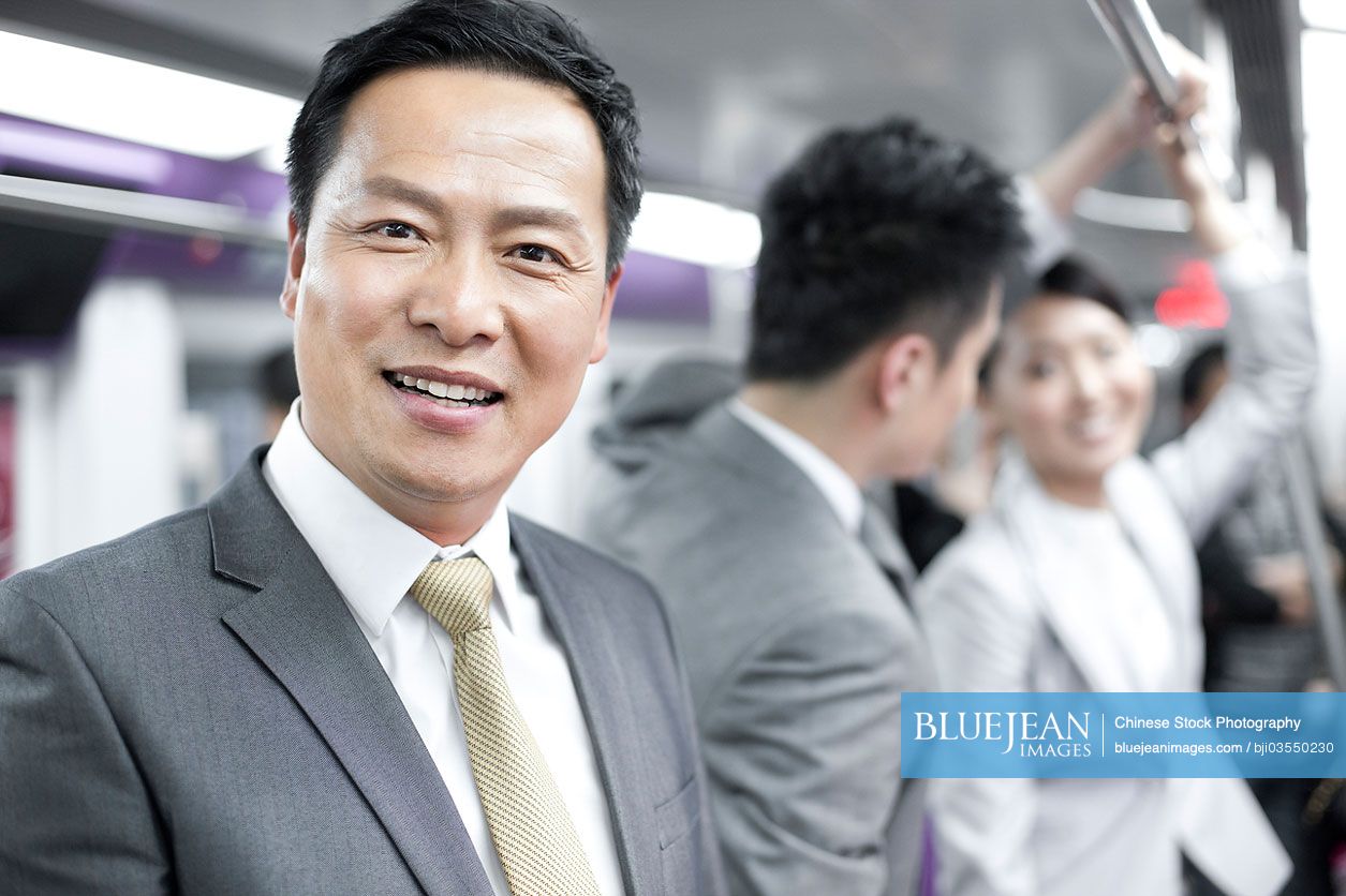 Cheerful Chinese businessman with partners in subway train-High-res ...