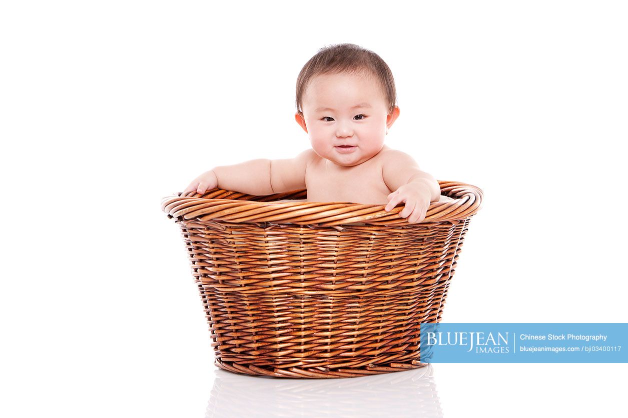 Cute Chinese baby girl sitting in basket-High-res stock photo for download