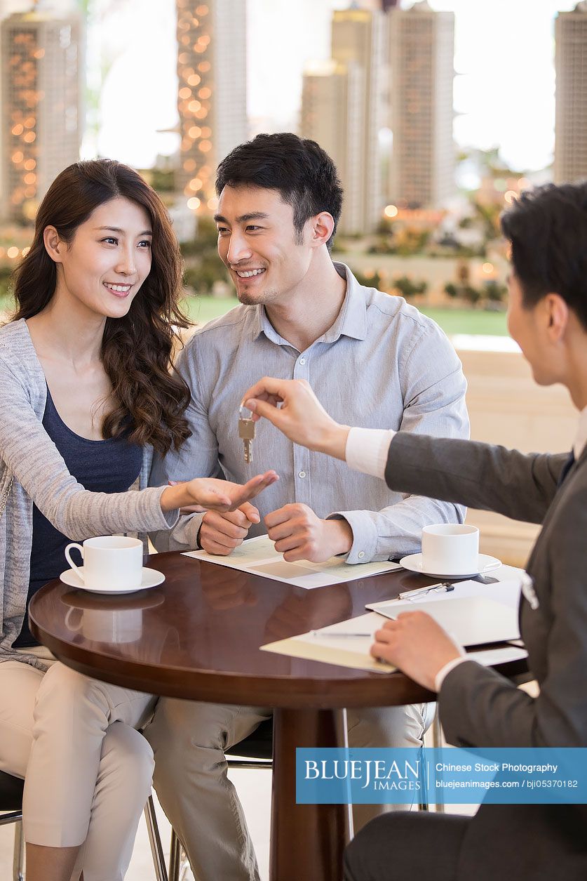 Happy young Chinese couple buying new house from realtor-High-res stock photo for download