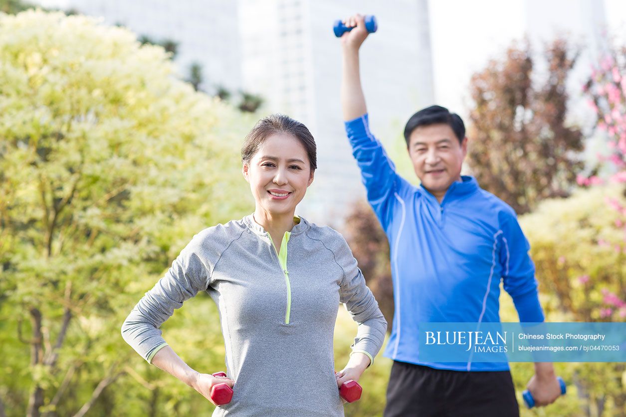 Happy mature Chinese couple exercising with dumbbell in park-High-res stock photo for download