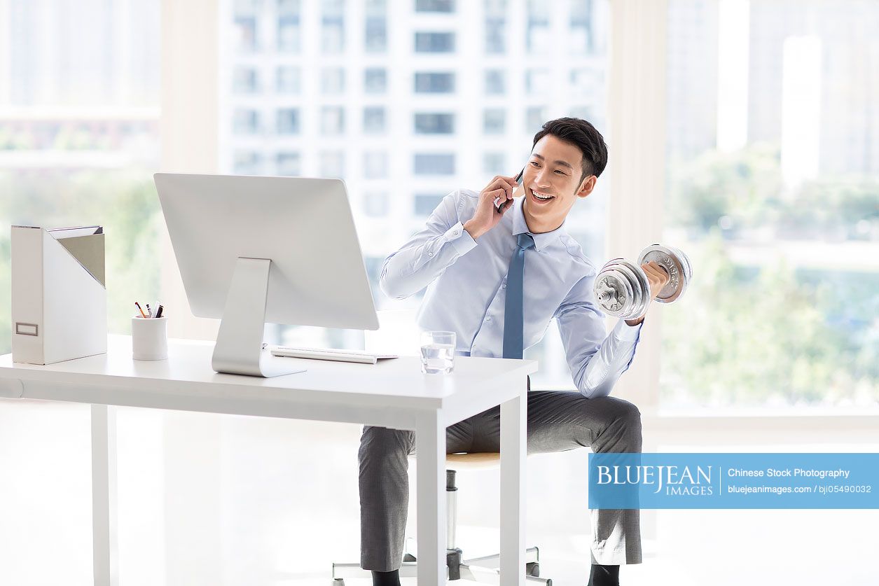 Young Chinese businessman exercising in office-High-res stock photo for ...