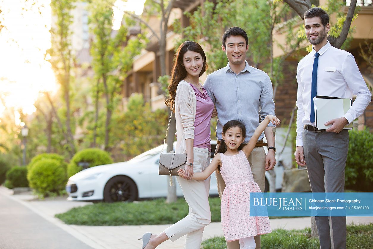 Happy young Chinese family receiving house key from real estate agent-High-res stock photo for ...