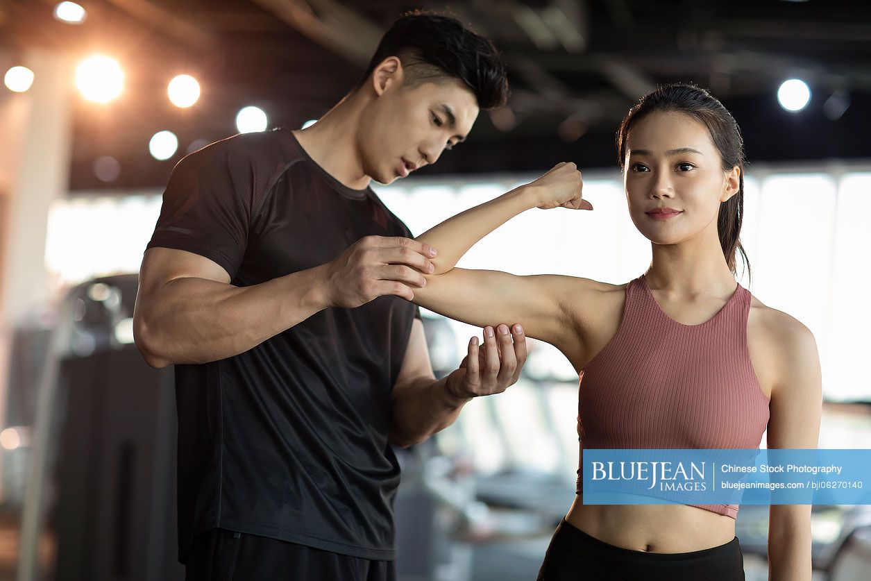 Young Chinese woman working out with personal trainer at gym-High-res ...