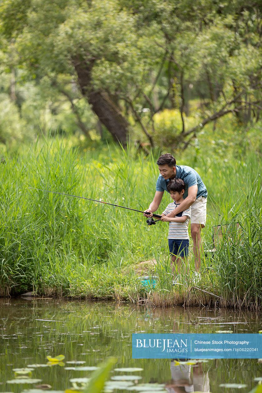 Happy Chinese father and son fishing by the river-High-res stock photo for download