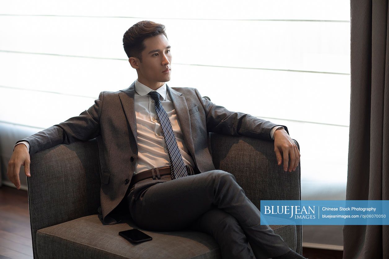 Young Chinese businessman sitting on sofa in hotel room-High-res stock ...