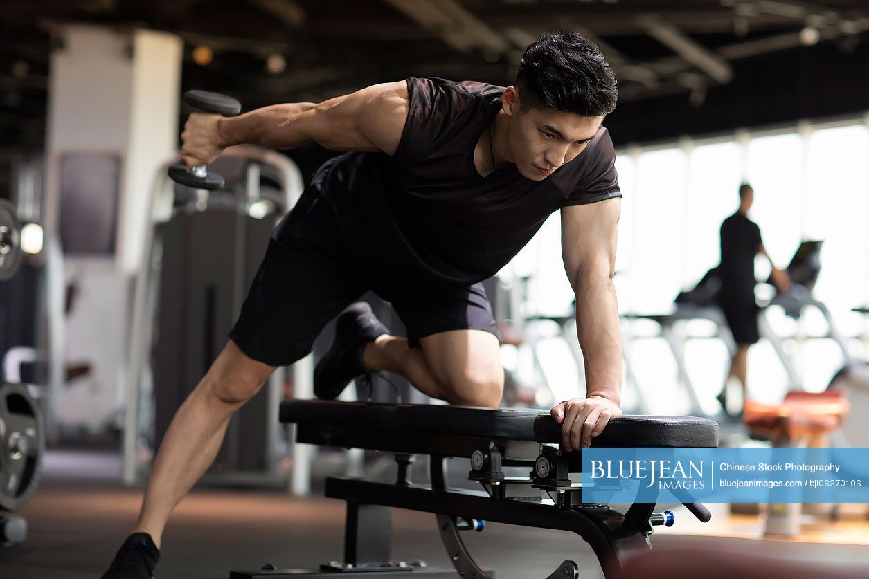 Young Chinese man working out with dumbbell at gym-High-res stock photo ...