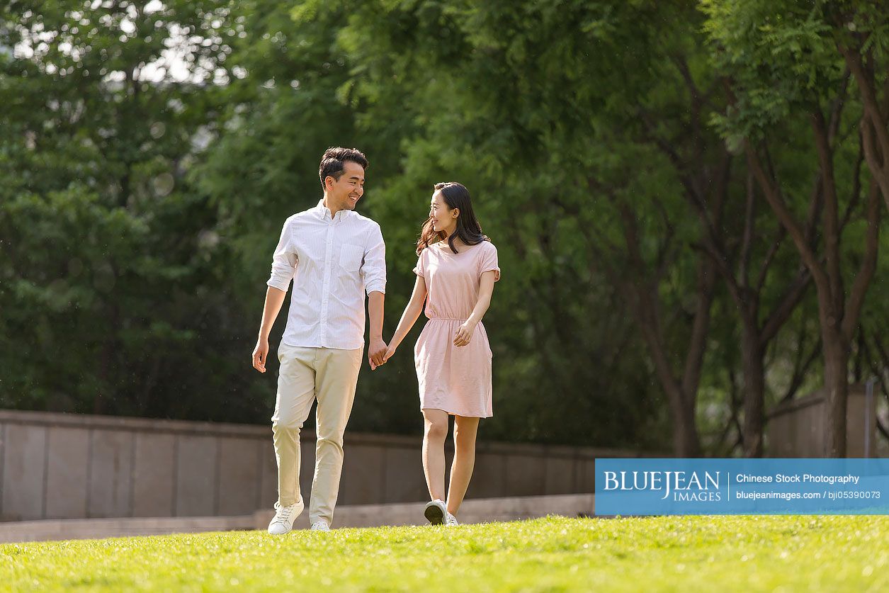 Happy young Chinese couple walking in park-High-res stock photo for download